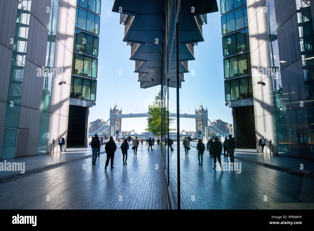 Tower bridge and office workers reflected in glass windows. More London ...
