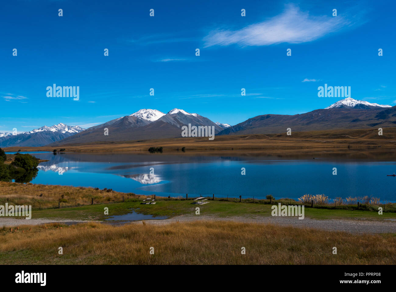 Snow capped peaks of Mount Sunday are reflected in the deep blue waters ...