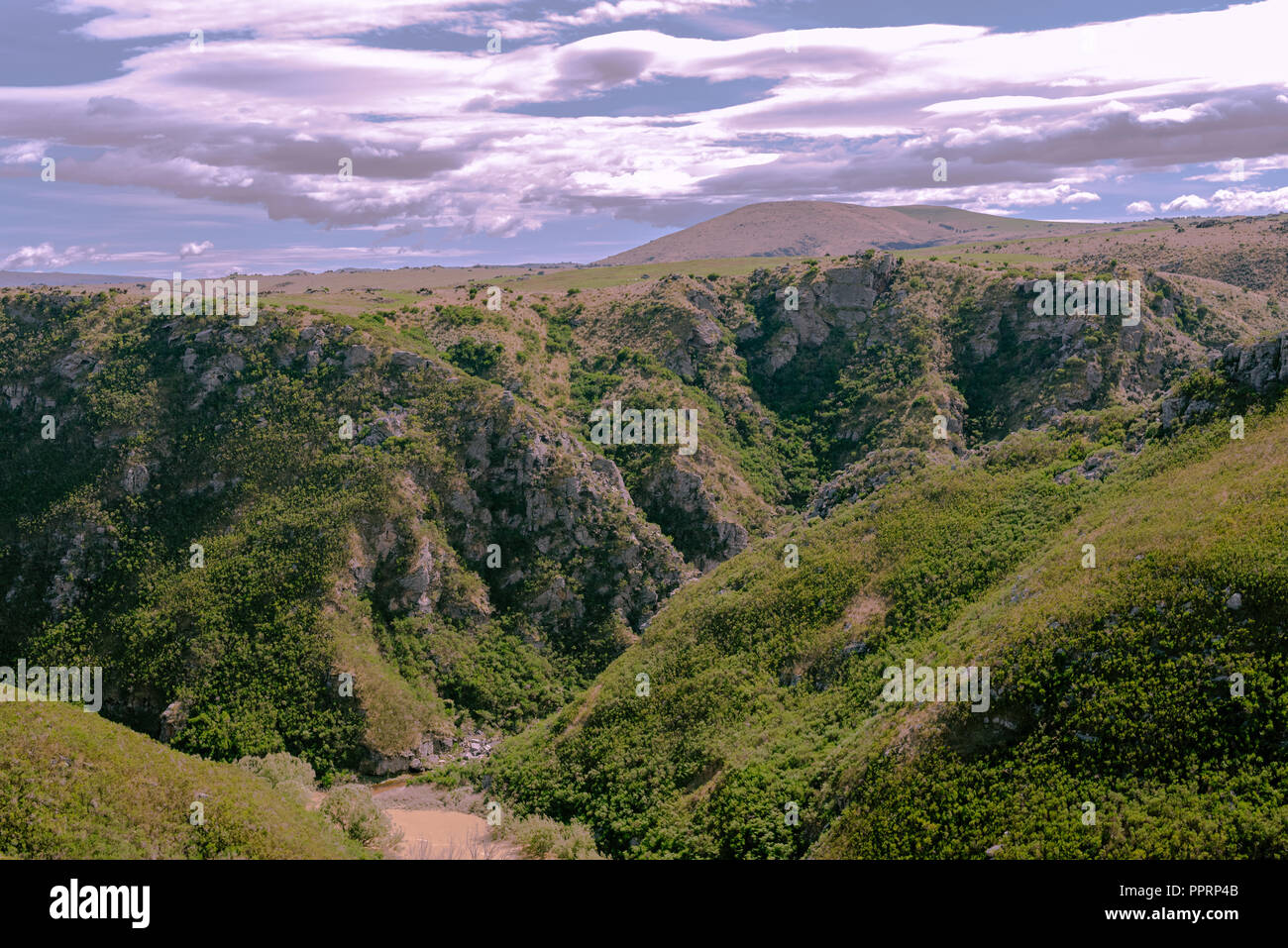 A photo that captures a deep green valley leading up to a flat plain ...