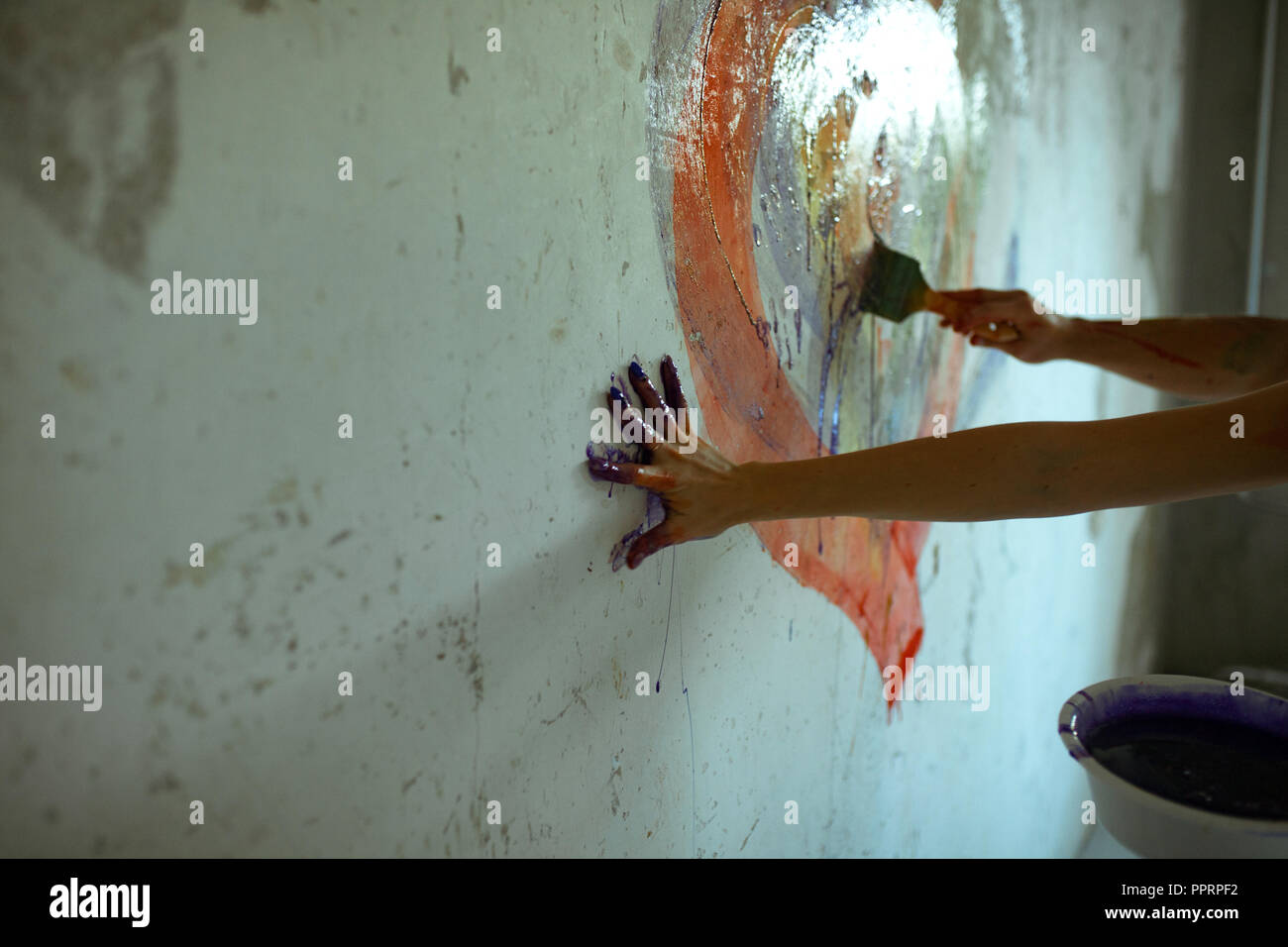 Human hands paint with brush on wall and make palm print with paint ...