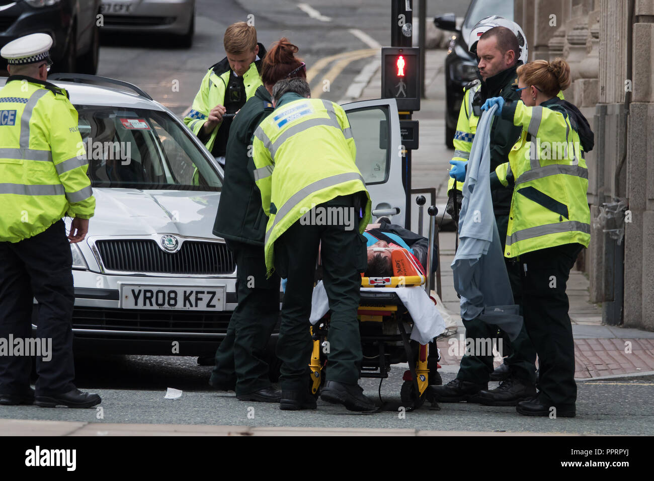 Ambulance paramedics and police officers help an injured man on a ...