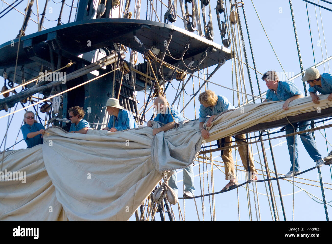 Sailors rolling up the sail on the spreader on the U.S. Brig Niagara ...
