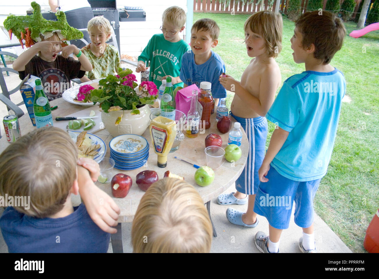 Kids around table probably sing happy birthday to a boy age 10 with a ...