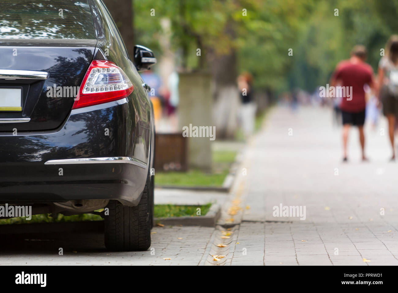 Back view part of black luxury shiny car parked on city pedestrian zone ...