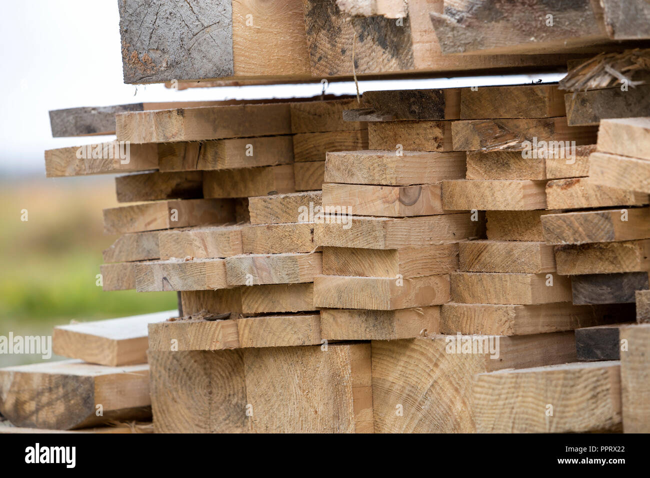 Close-up of piled stack of natural brown uneven rough wooden boards lit ...
