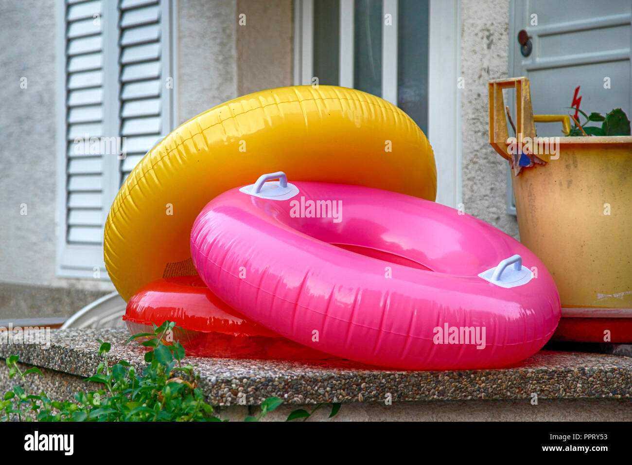Inflatable beach floats shaped like doughnut rings rest on porch ready ...