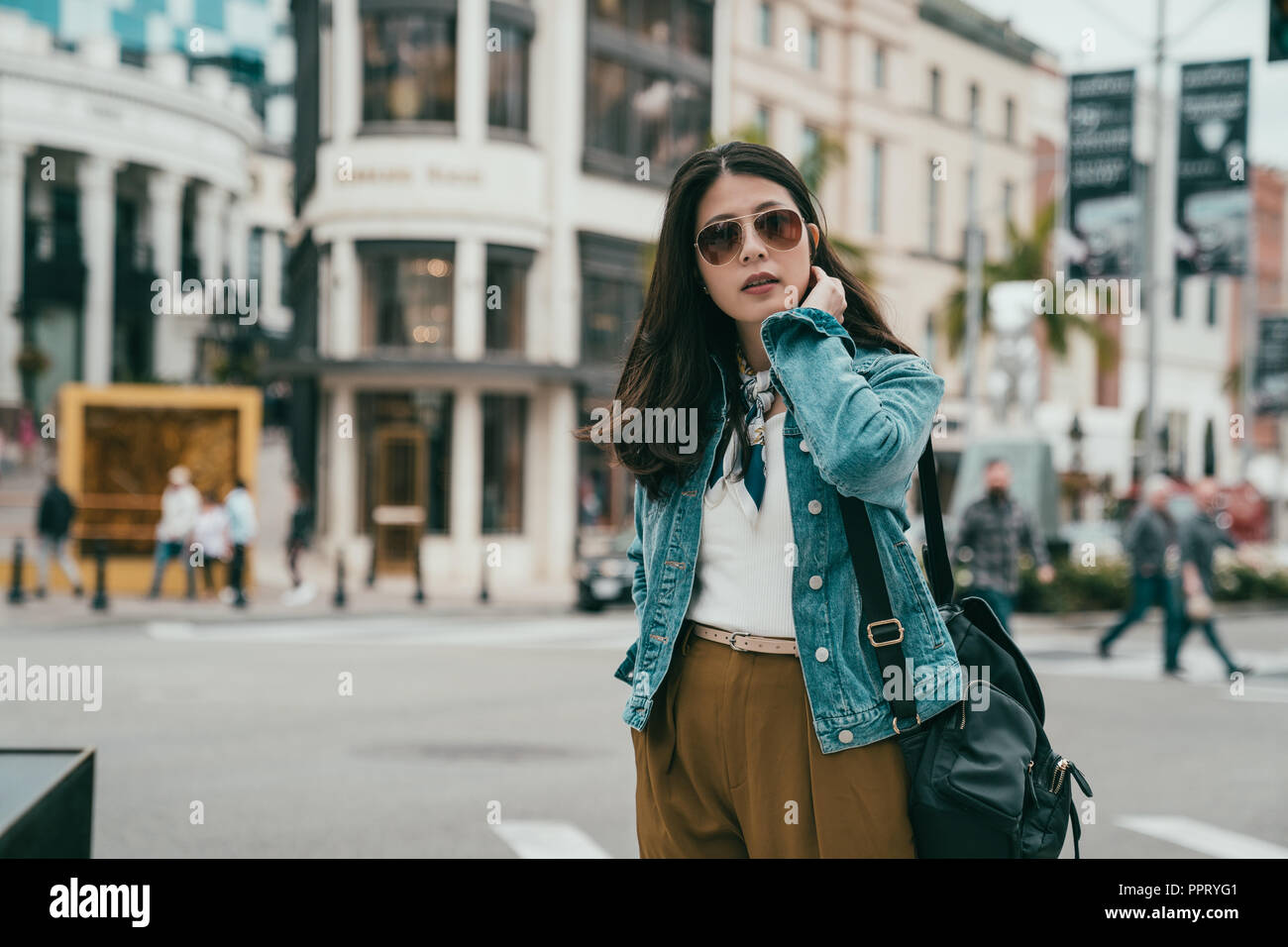 pretty lady stopped while she is crossing the road and looking at the ...