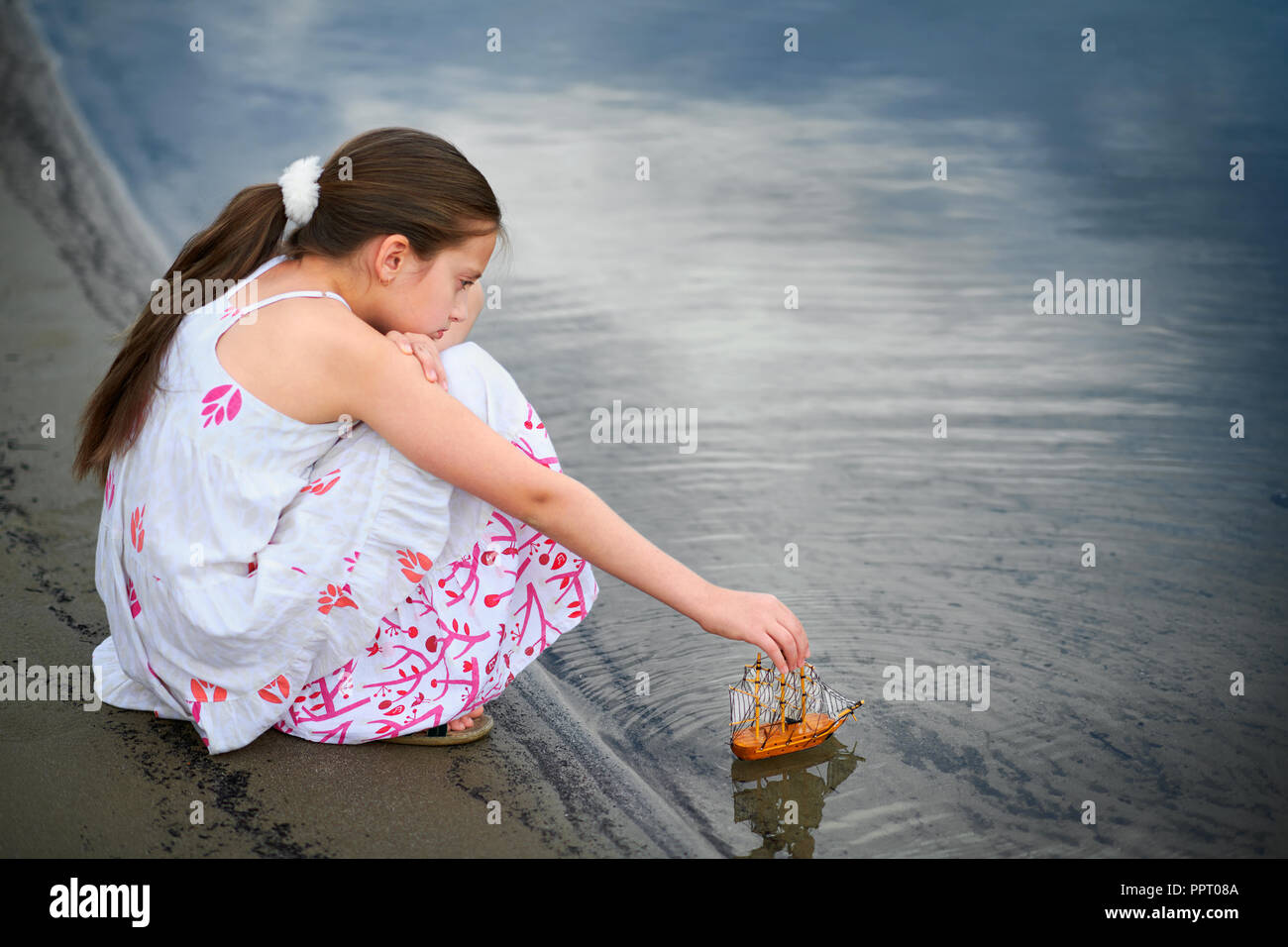 girl child playing with a toy sailing ship by the river Stock Photo - Alamy