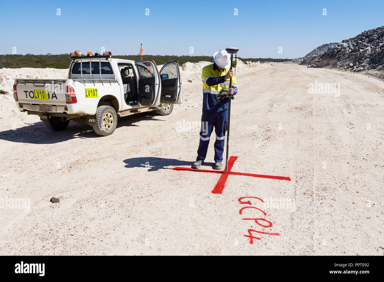 Surveyor marking reference point for use with drone to measure ore ...