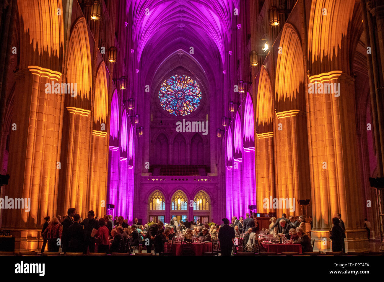 Guests eat dinner under colorfully lit arches at the National Cathedral ...