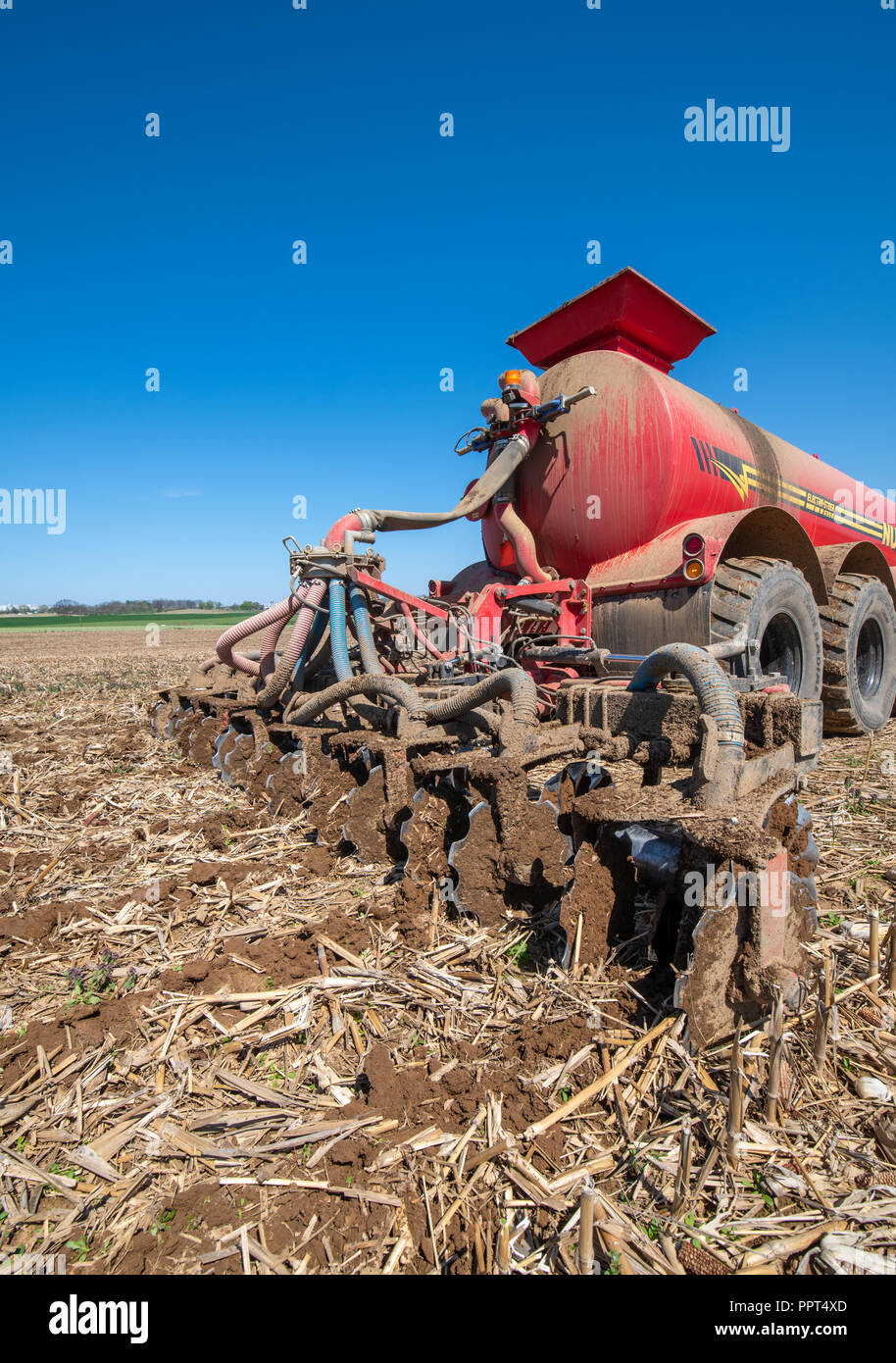 A tractor driven tanker injects duck manure into corn stubble to help ...
