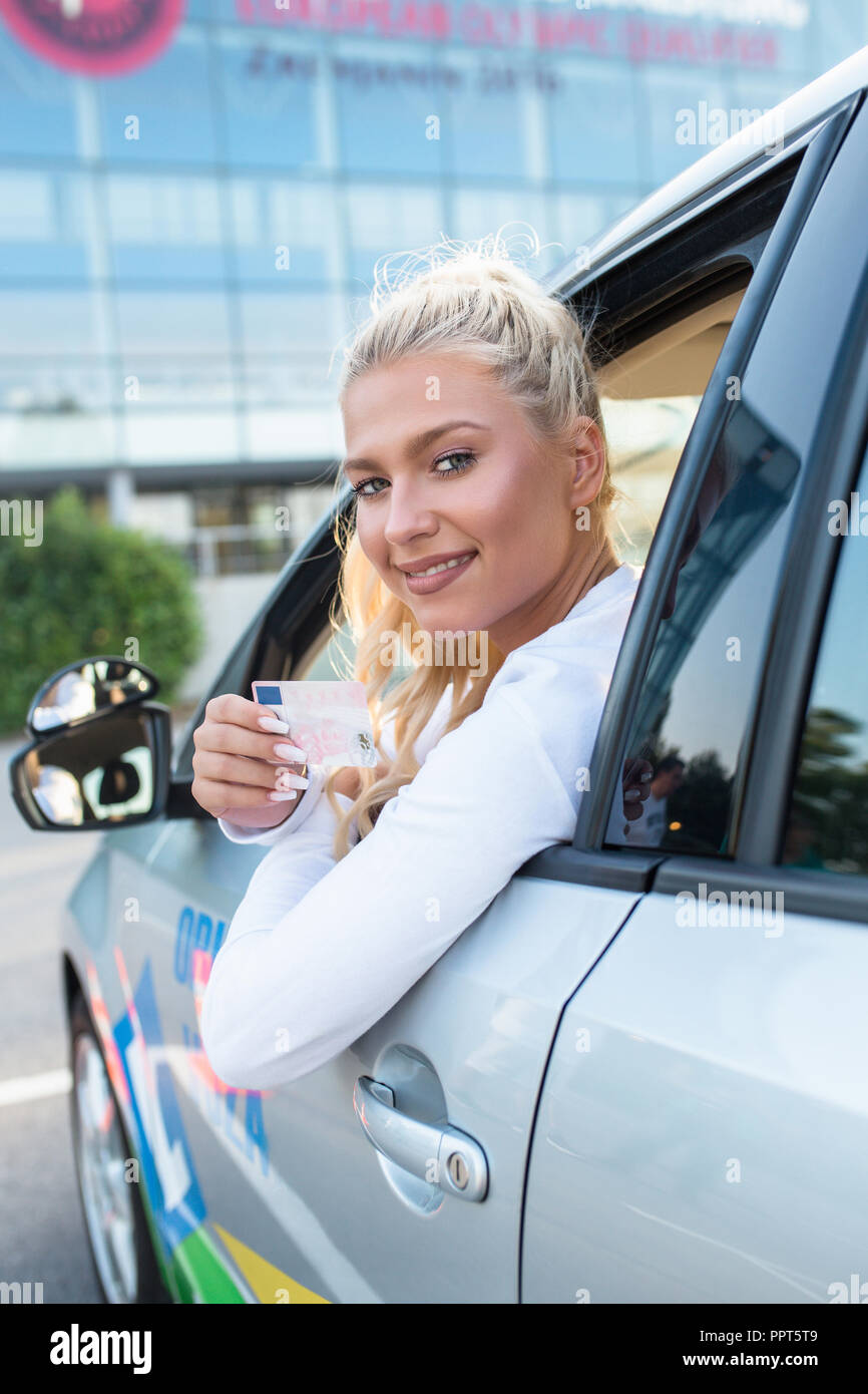 Driving school. Attractive young girl proudly showing her drivers ...