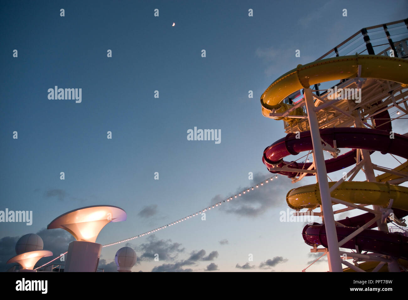 A water slide, the moon and lights, on the top deck of a cruise ship ...