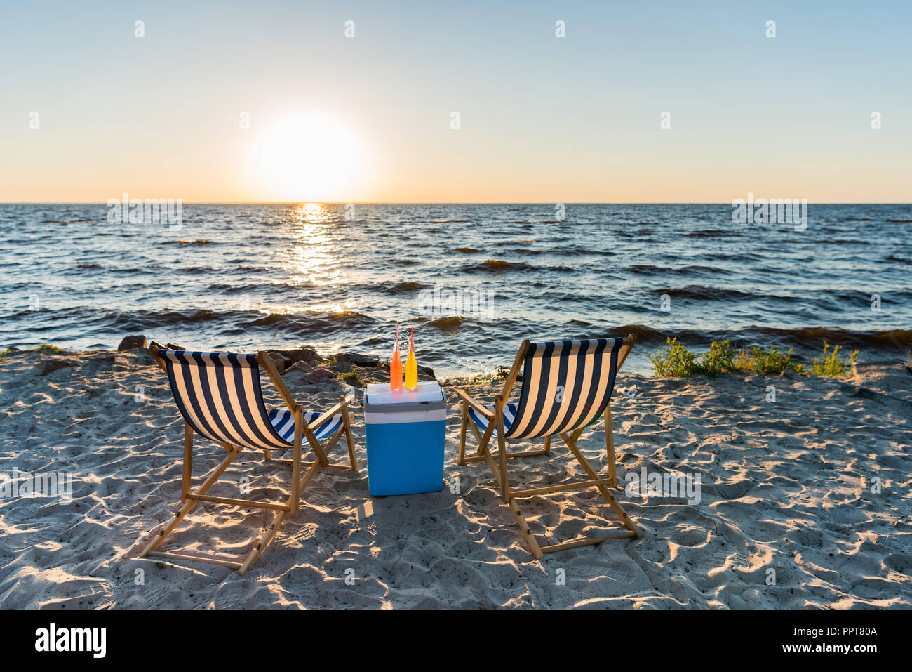 summer beverages on cooler and chaise lounges on sandy beach at sunset ...