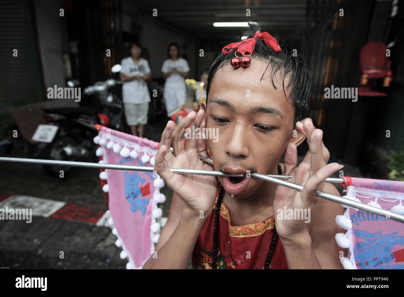 Young spirit medium with large metal spikes piercing through cheeks and ...