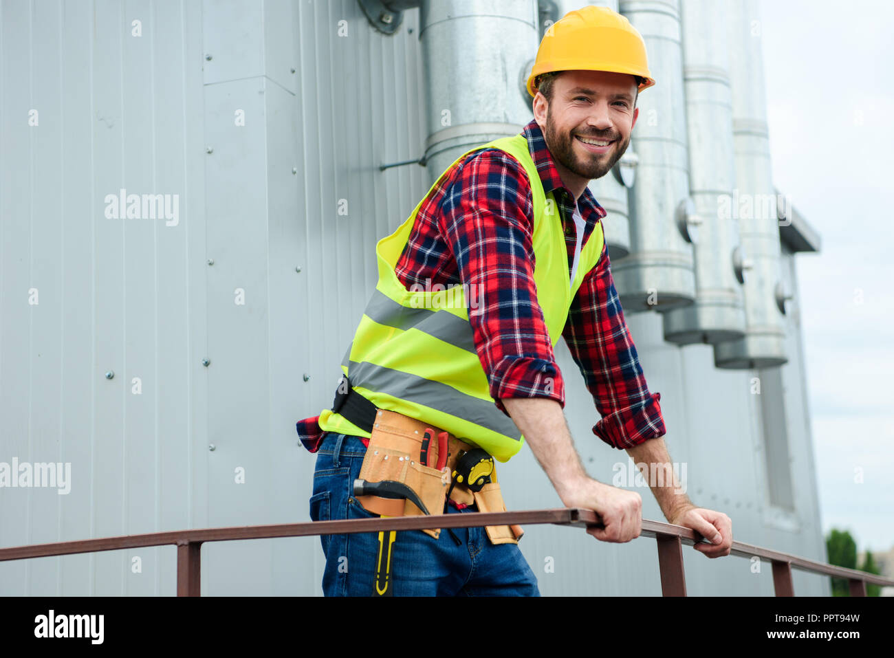 male professional architect in safety vest and helmet posing on roof ...