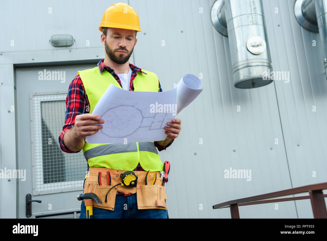 male architect in safety vest and helmet working with blueprints Stock ...