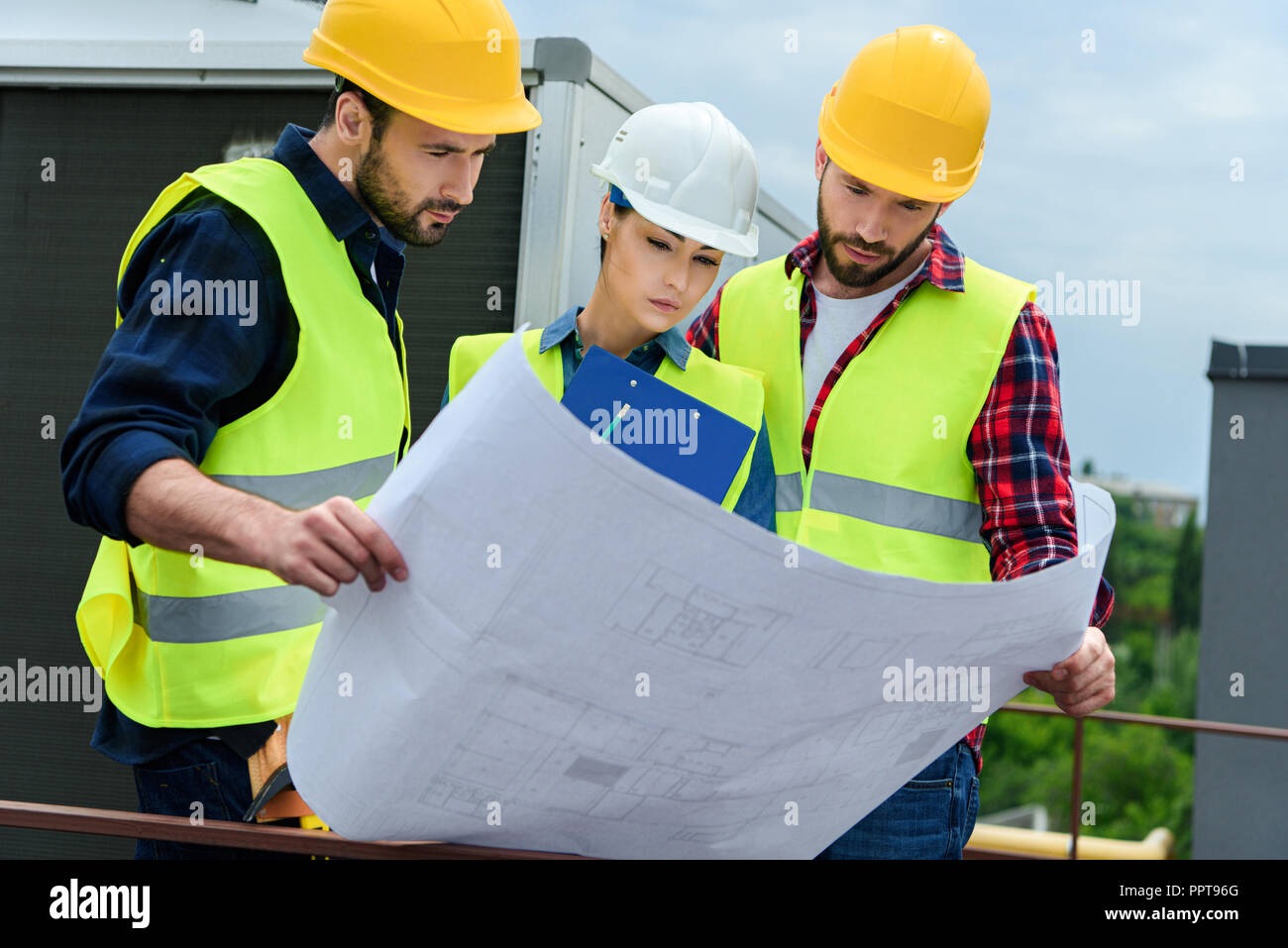 professional engineers in hardhats working with blueprint and clipboard ...