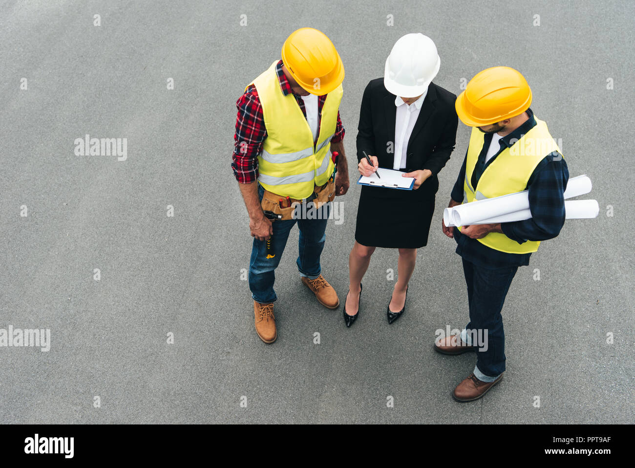 overhead view of female architect and male workers in hardhats working ...