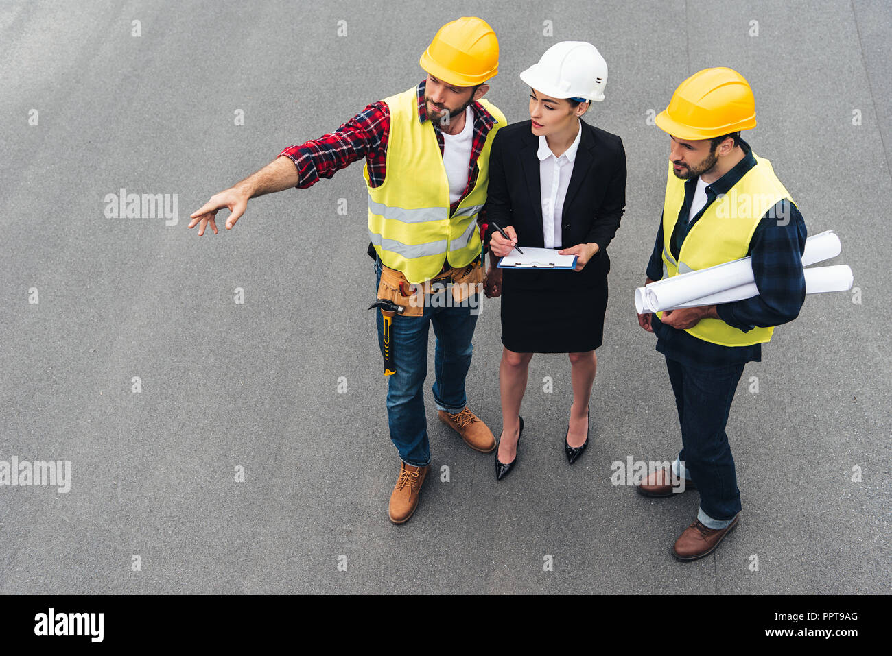 overhead view of female engineer and male workers with clipboard and ...