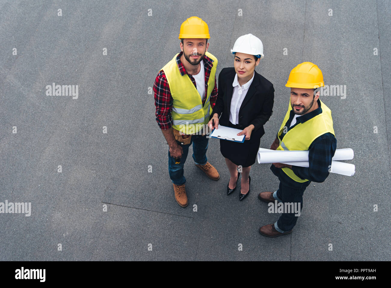 overhead view of female engineer and male workers with clipboard and ...