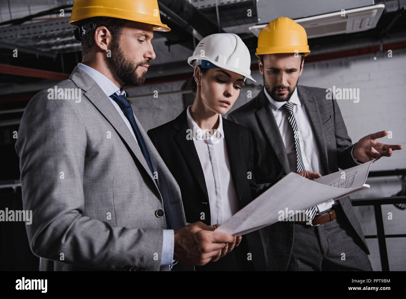architects and engineers in suits and hardhats working with blueprint ...