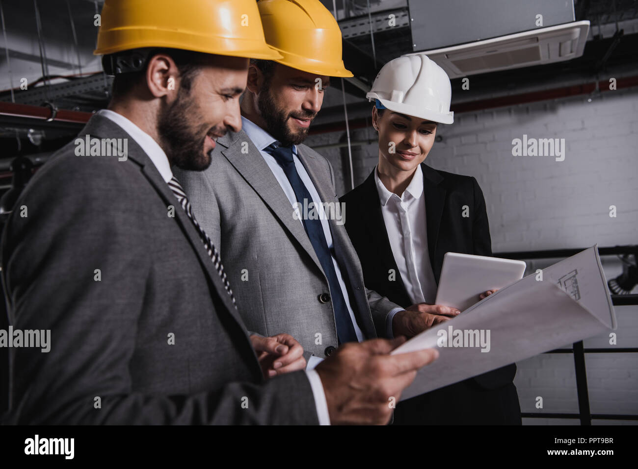 engineers in suits and hardhats working with blueprint and digital ...