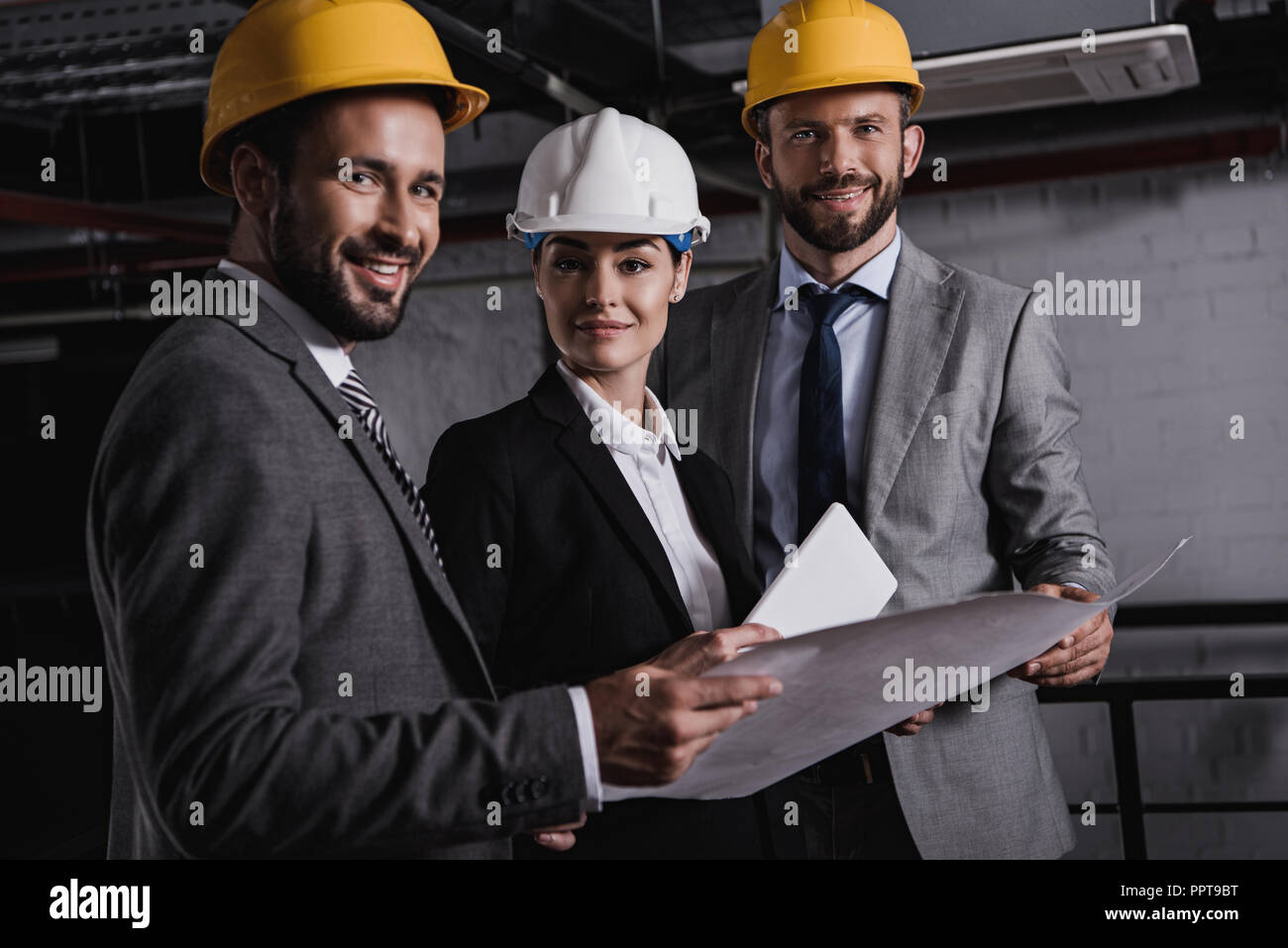 architects in suits and helmets working with blueprint and digital ...