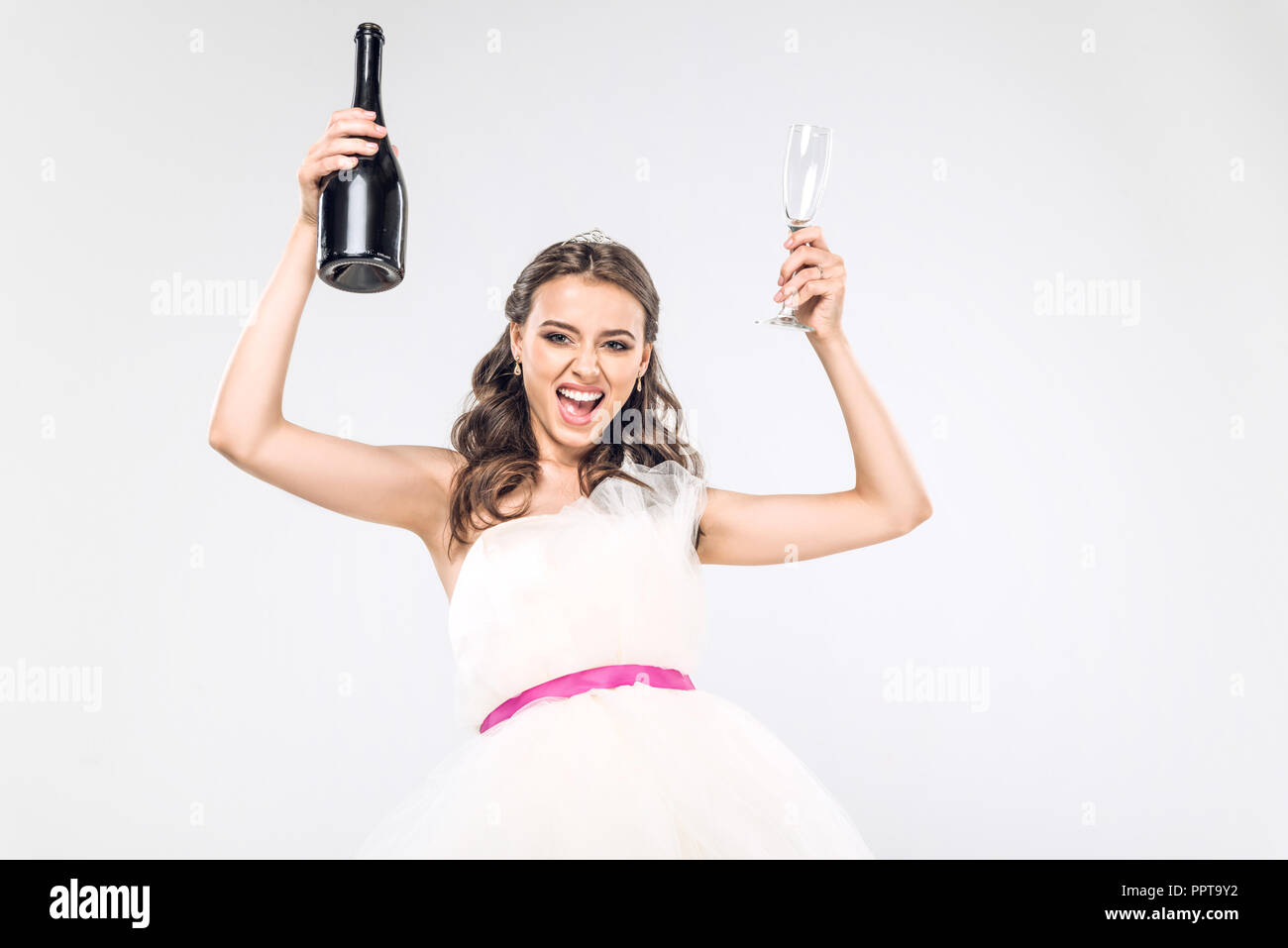 partying young bride in wedding dress with champagne bottle and glass ...