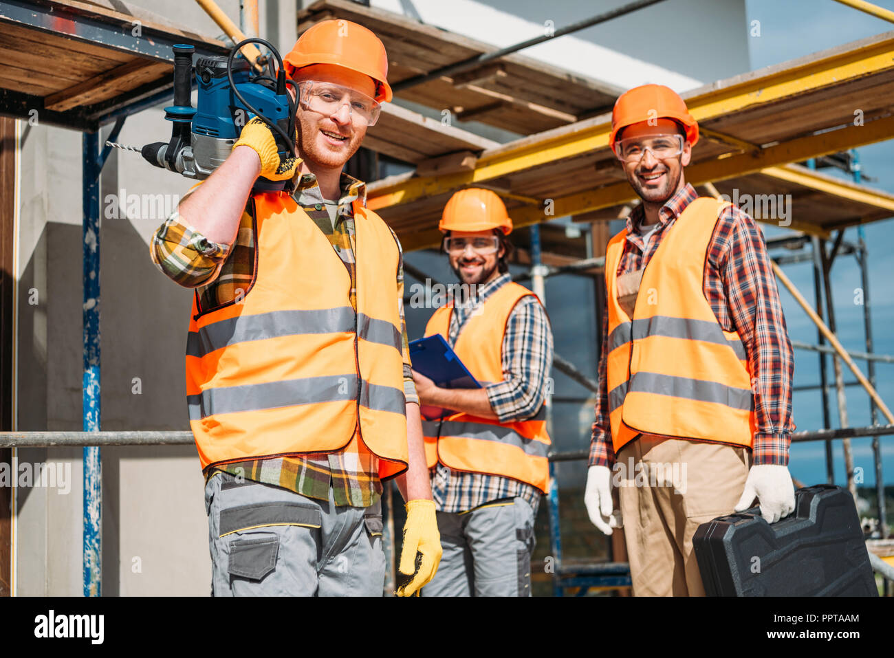group of smiling builders with building equipment standing at ...