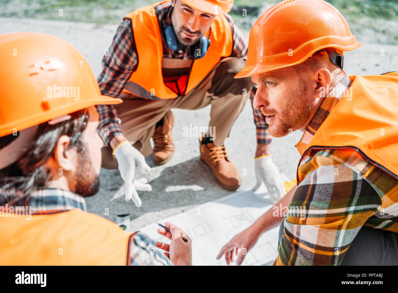 close-up shot of group of builders in hard hats having conversation ...
