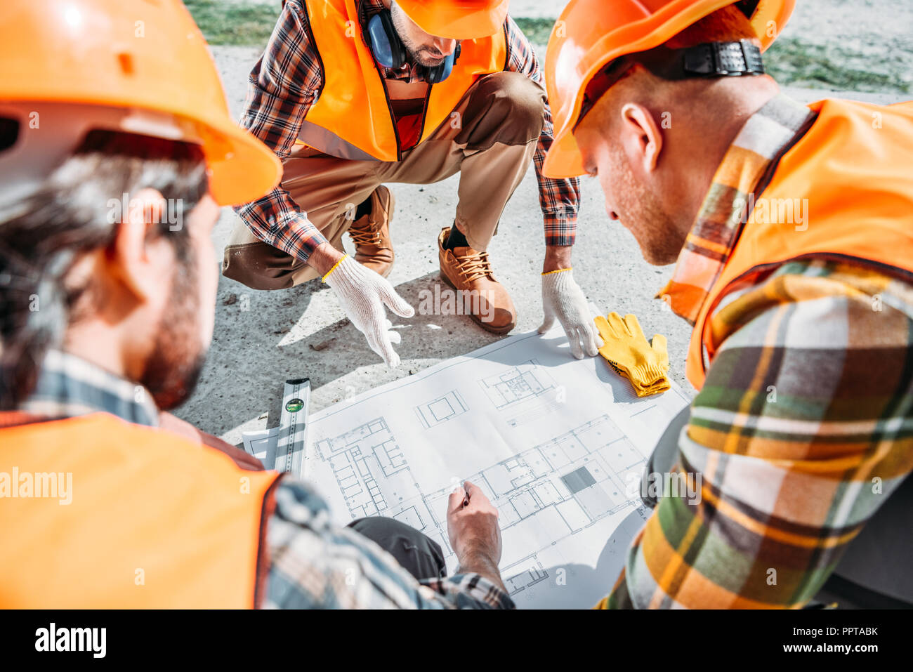 close-up shot of group of builders in hard hats having conversation ...