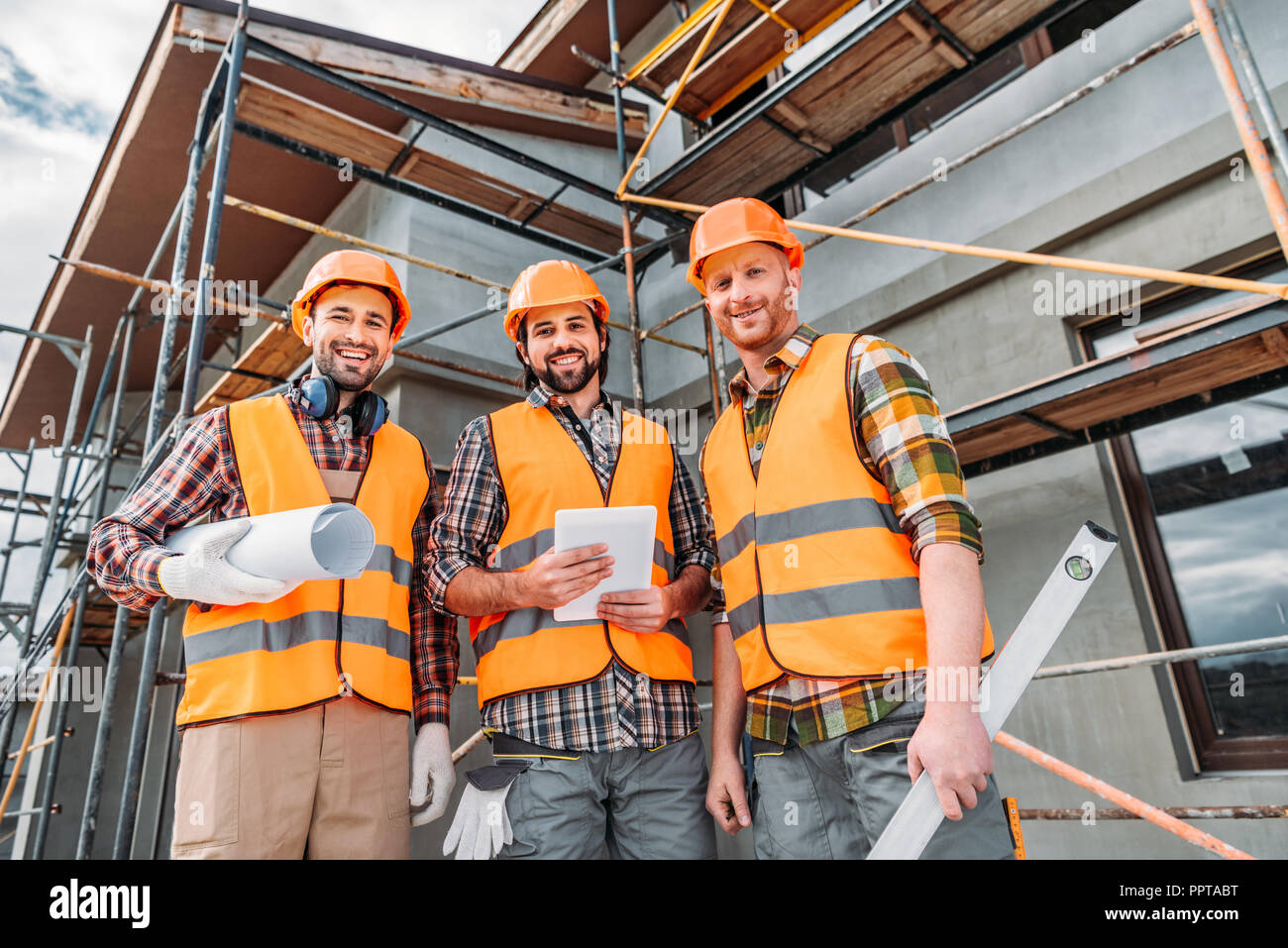 bottom view of group of smiling builders with blueprint and tablet ...