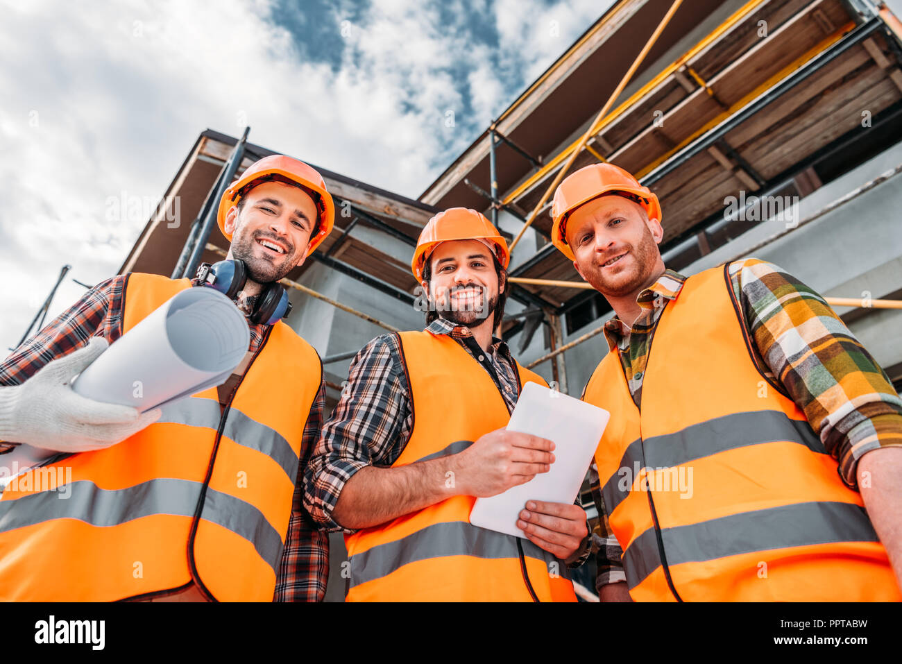 bottom view of group of builders with blueprint and tablet looking at ...