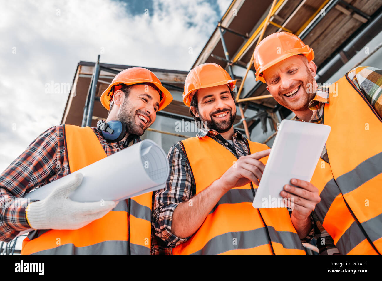 bottom view of group of builders with blueprint and tablet at ...