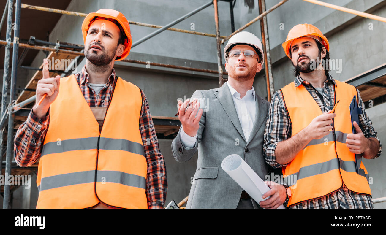 wide shot of builders and architect looking away in front of ...