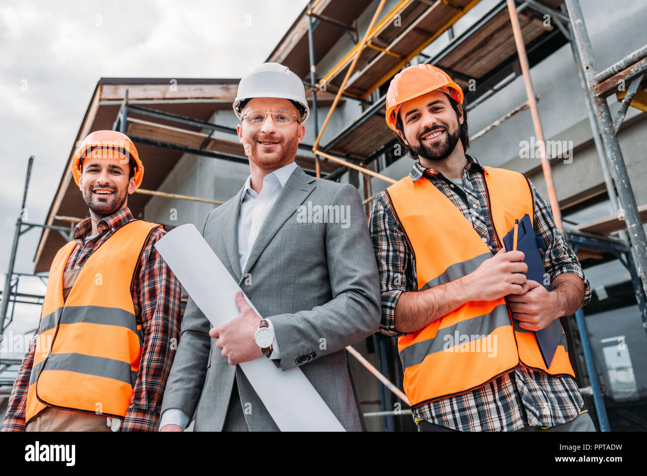 bottom view of builders and architect with blueprint looking at camera ...