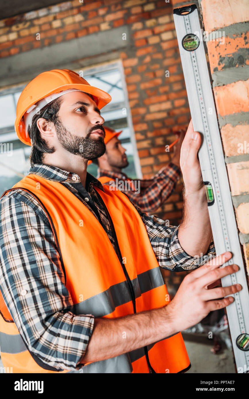 side view of handsome builder using bubble level at construction site ...