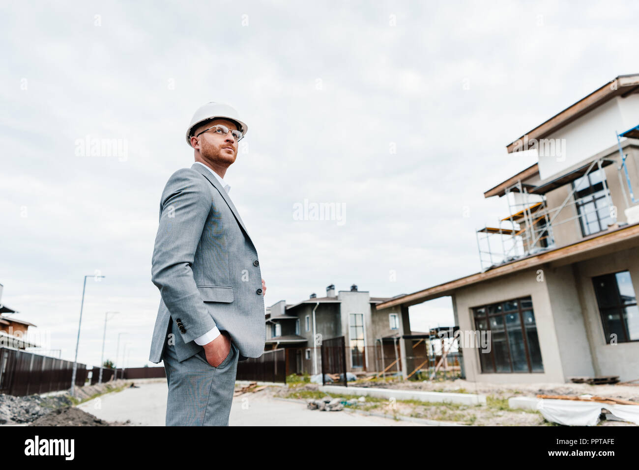 successful architect in suit and hard hat standing in front of building ...