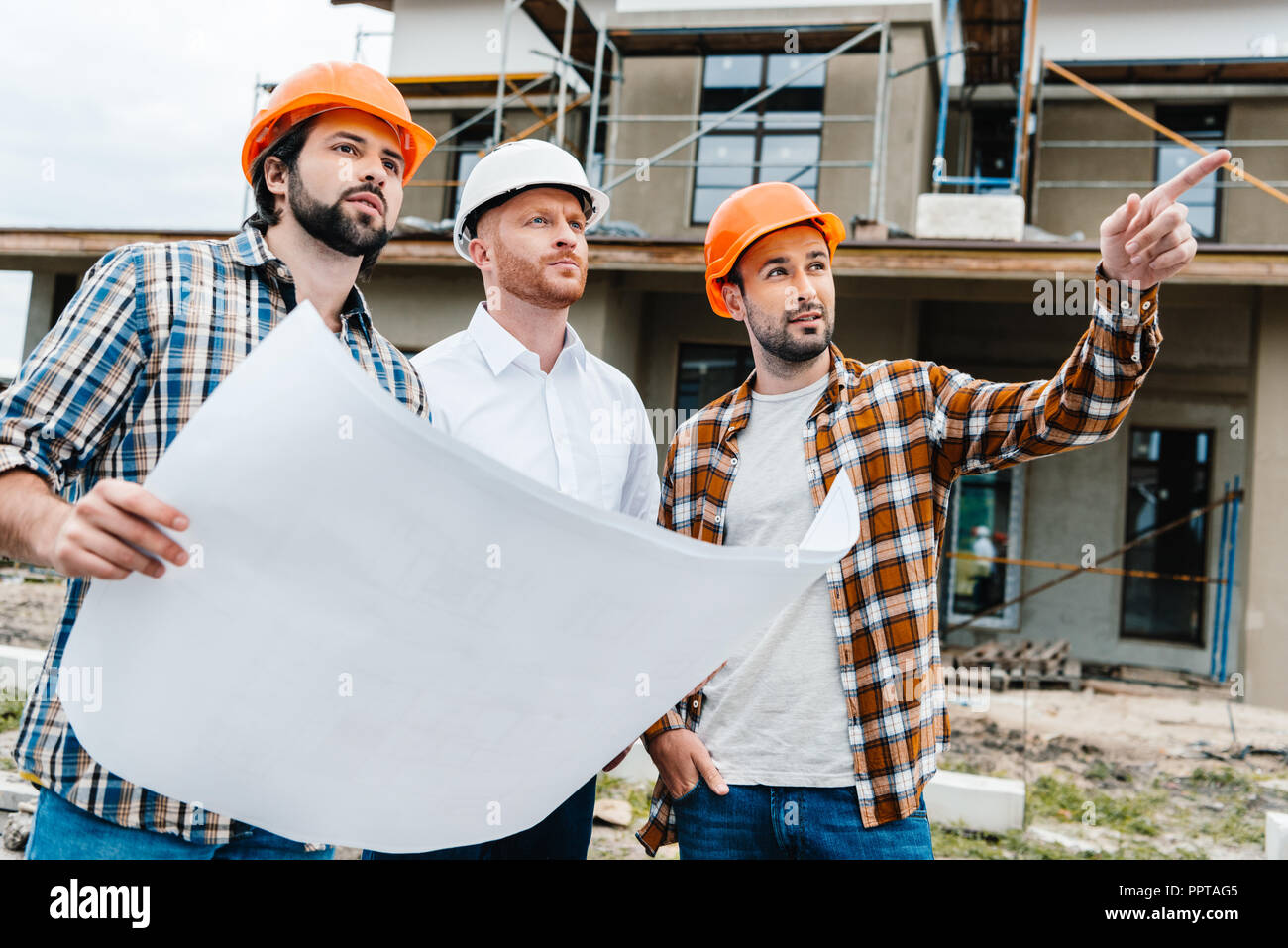 group of architects with building plan standing in front of ...
