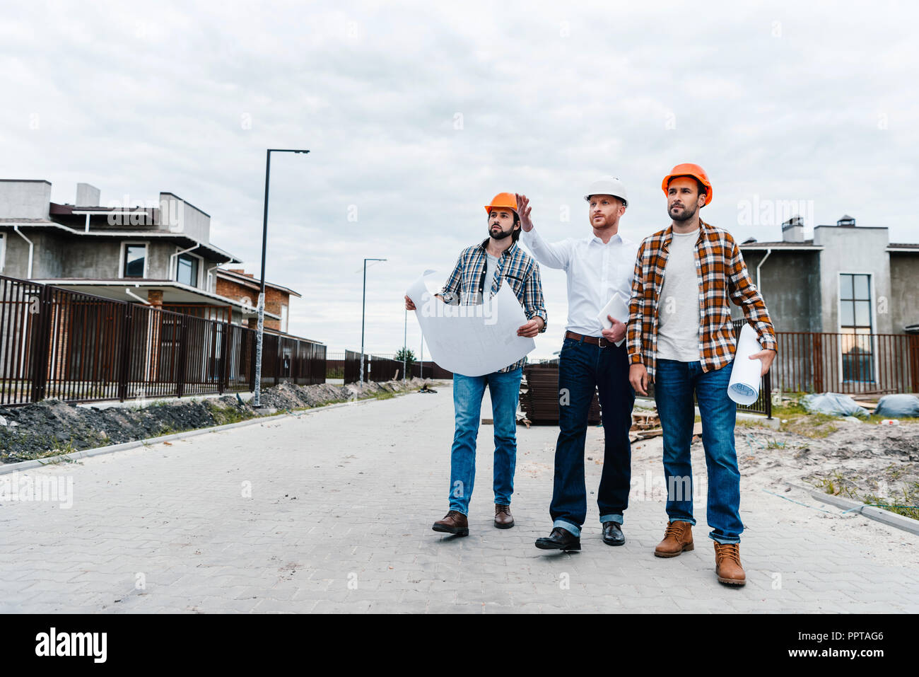 group of architects walking by constructing street with blueprints ...