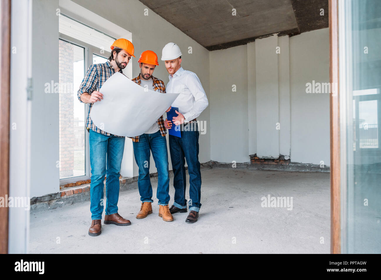 group of architects with blueprint having conversation inside of ...