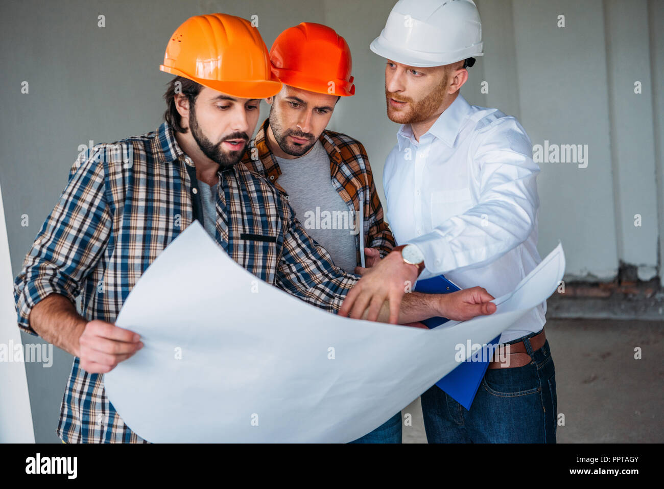 group of adult architects with blueprint having conversation inside of ...
