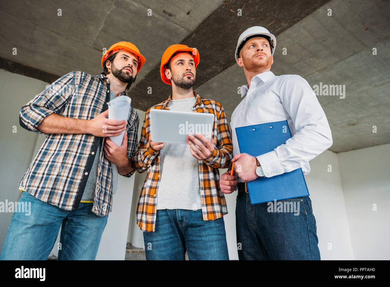 bottom view of group of architects with tablet looking away inside of ...