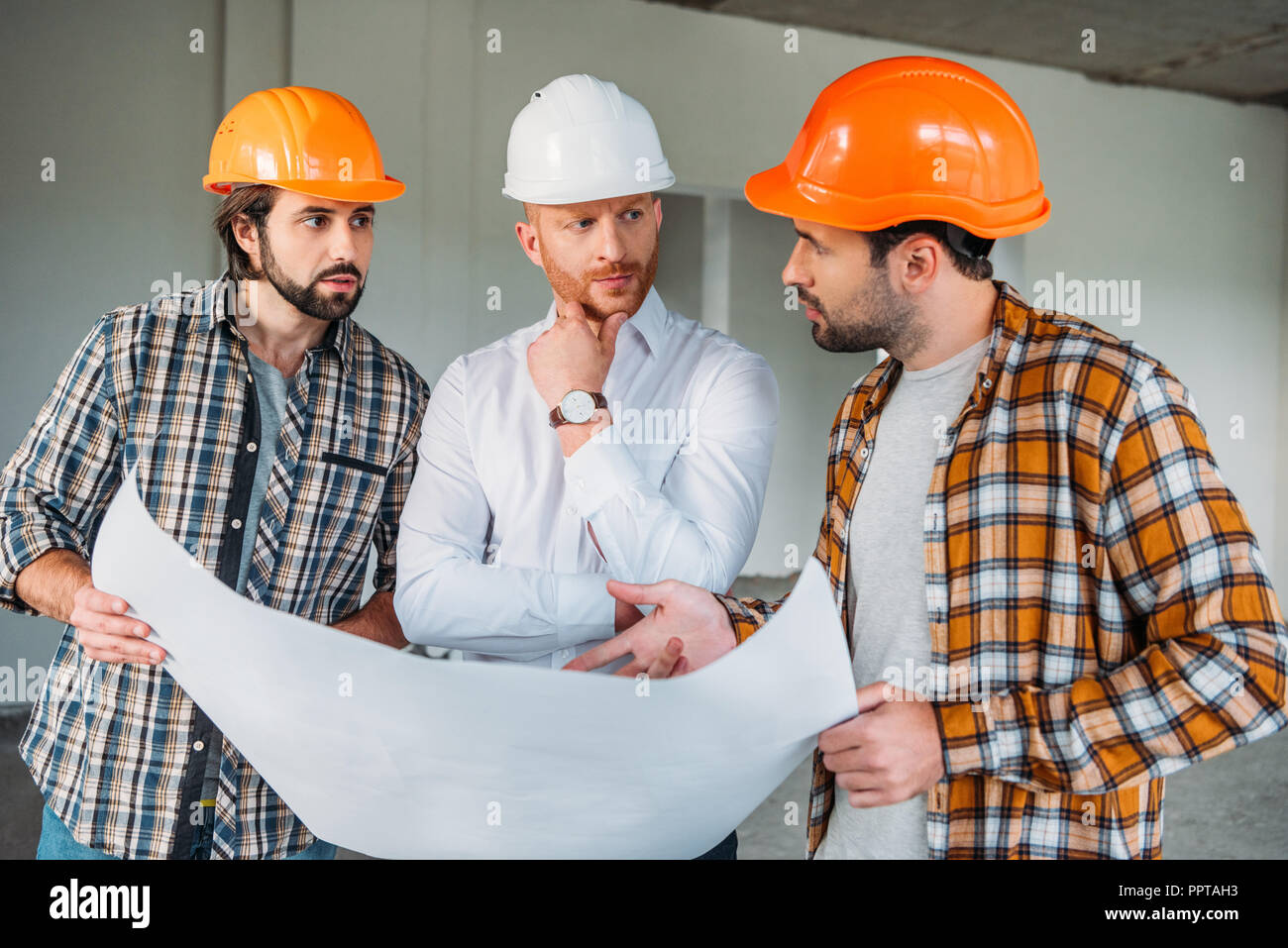 group of handsome architects with blueprint having conversation inside ...