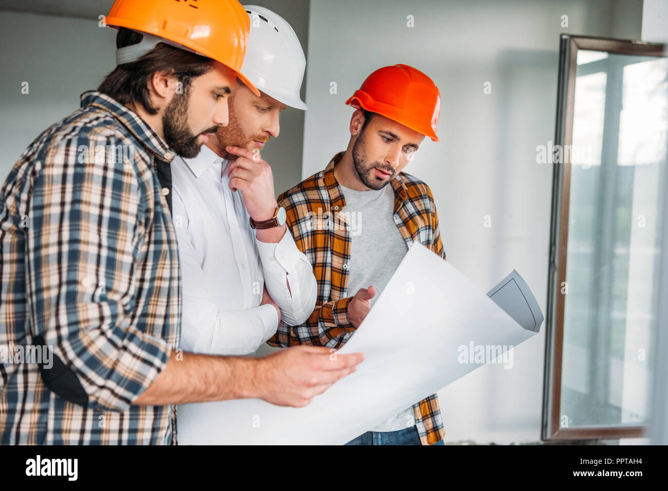group of architects with blueprint inside of constructing building ...