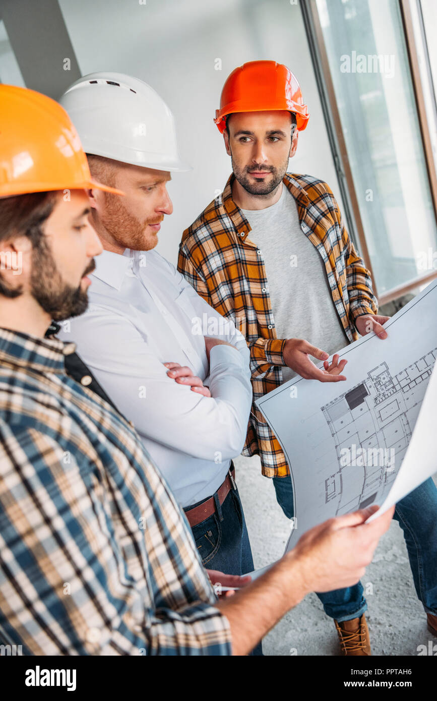 group of architects with blueprint having conversation inside of ...