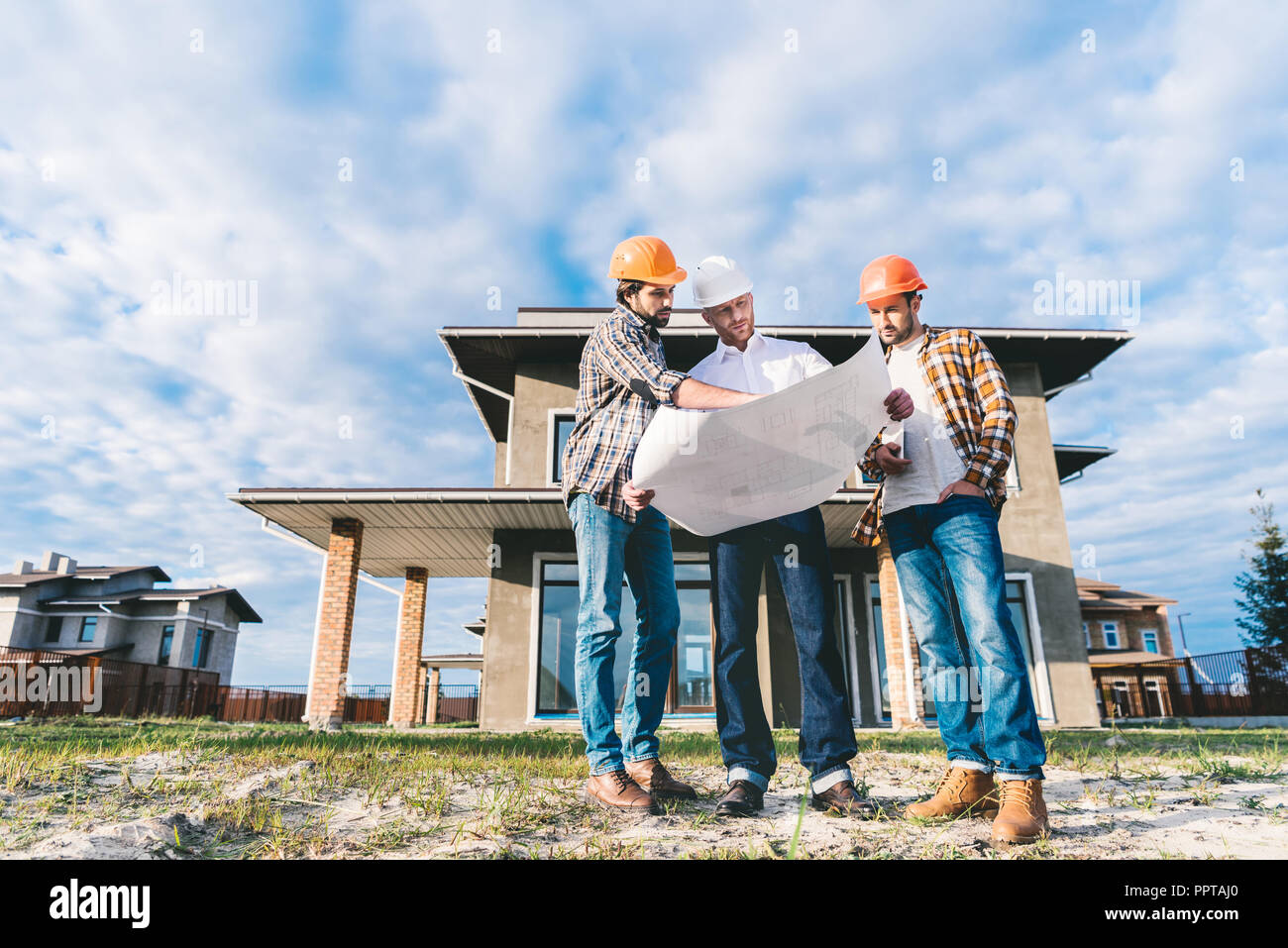 bottom view of group of architects with blueprint in garden at ...