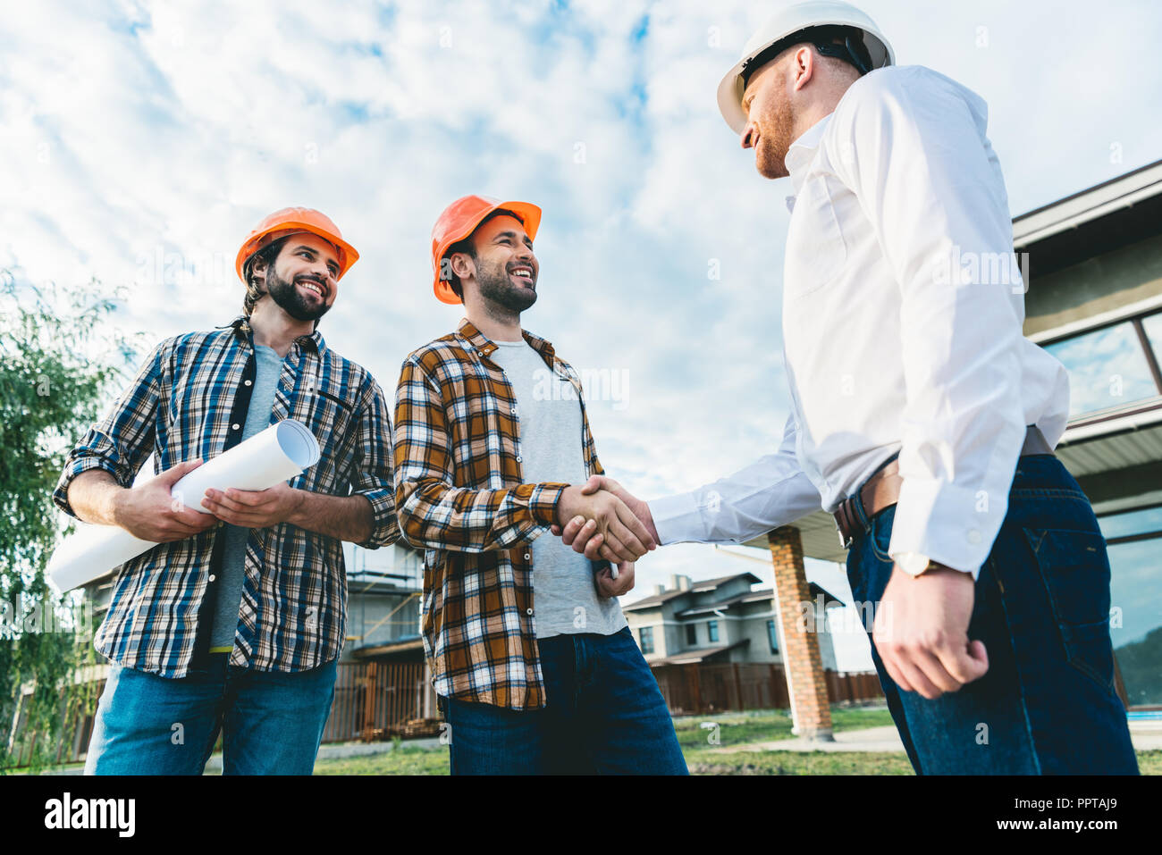 group of architects having conversation in garden at construction site ...