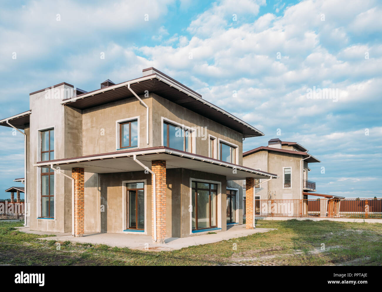 unfinished modern concrete buildings with green yards under cloudy sky ...